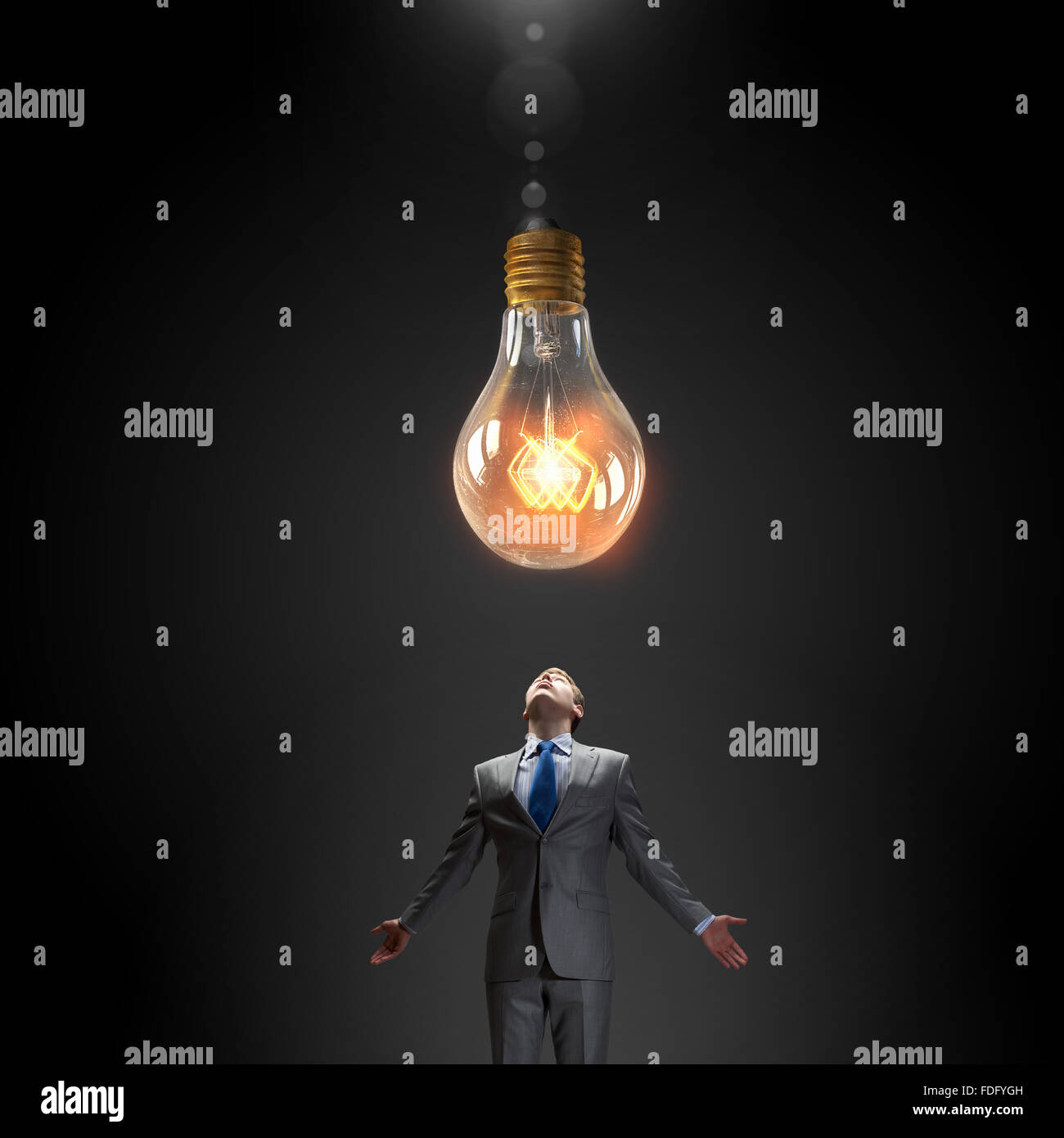 Young businessman looking up at glass glowing light bulb Stock Photo ...