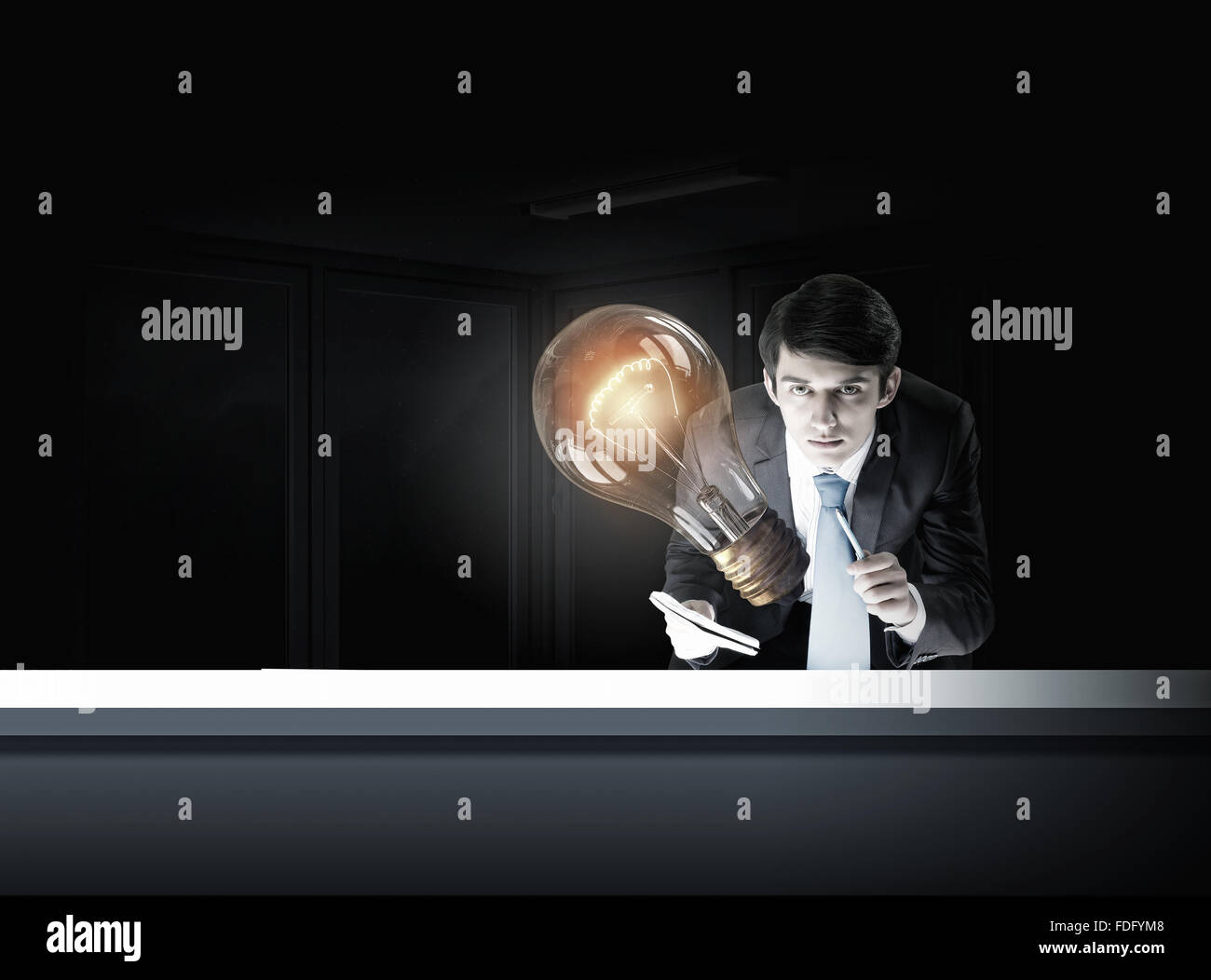 Young businessman examining glass glowing light bulb Stock Photo - Alamy