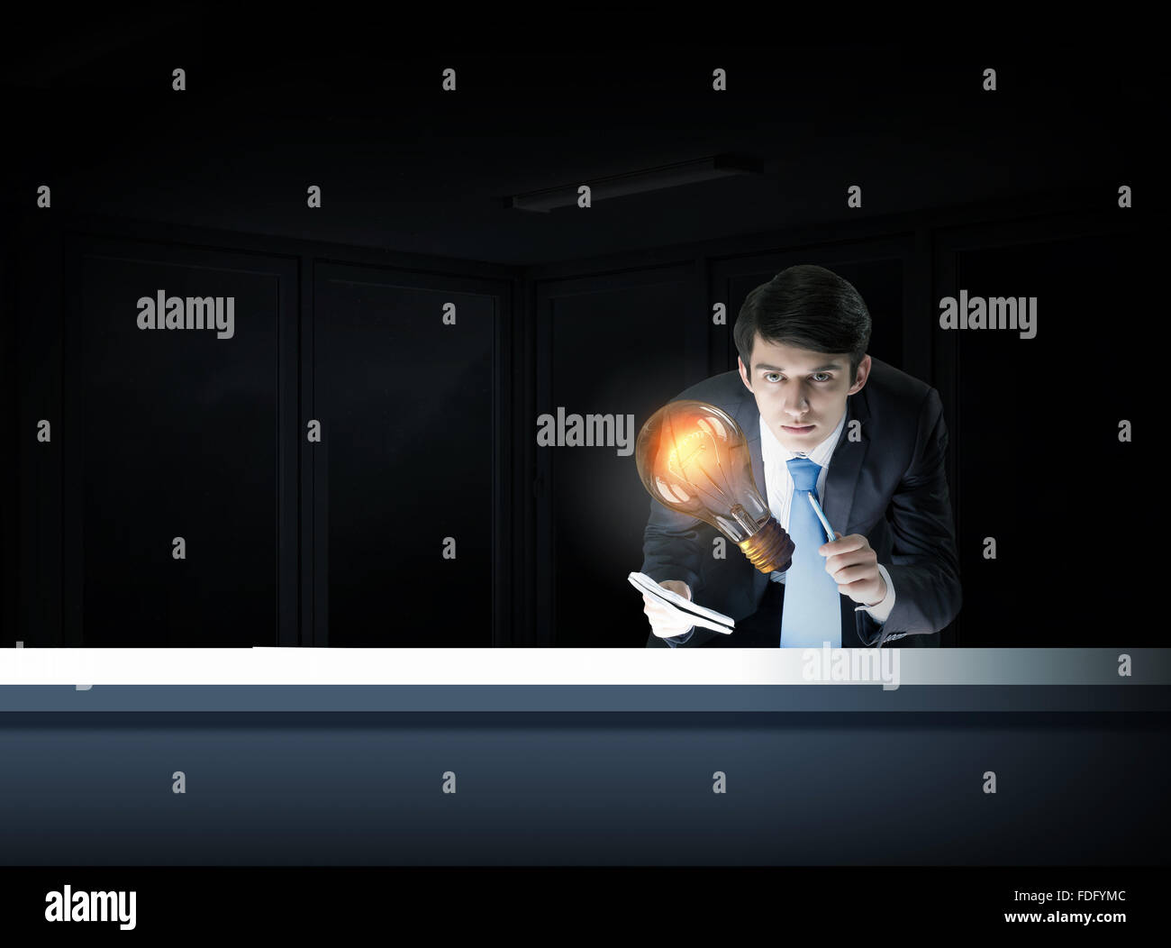 Young businessman examining glass glowing light bulb Stock Photo - Alamy