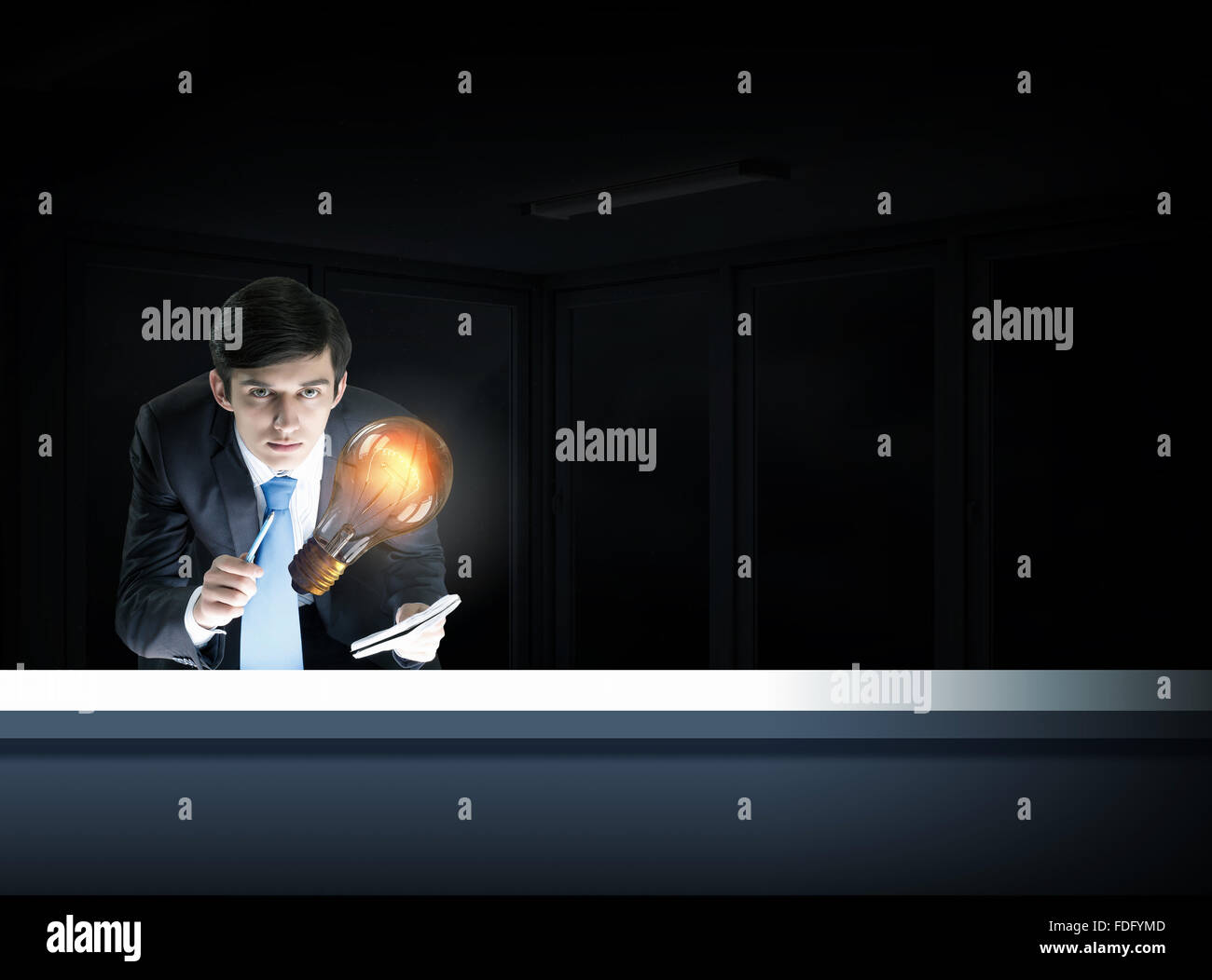 Young businessman examining glass glowing light bulb Stock Photo - Alamy