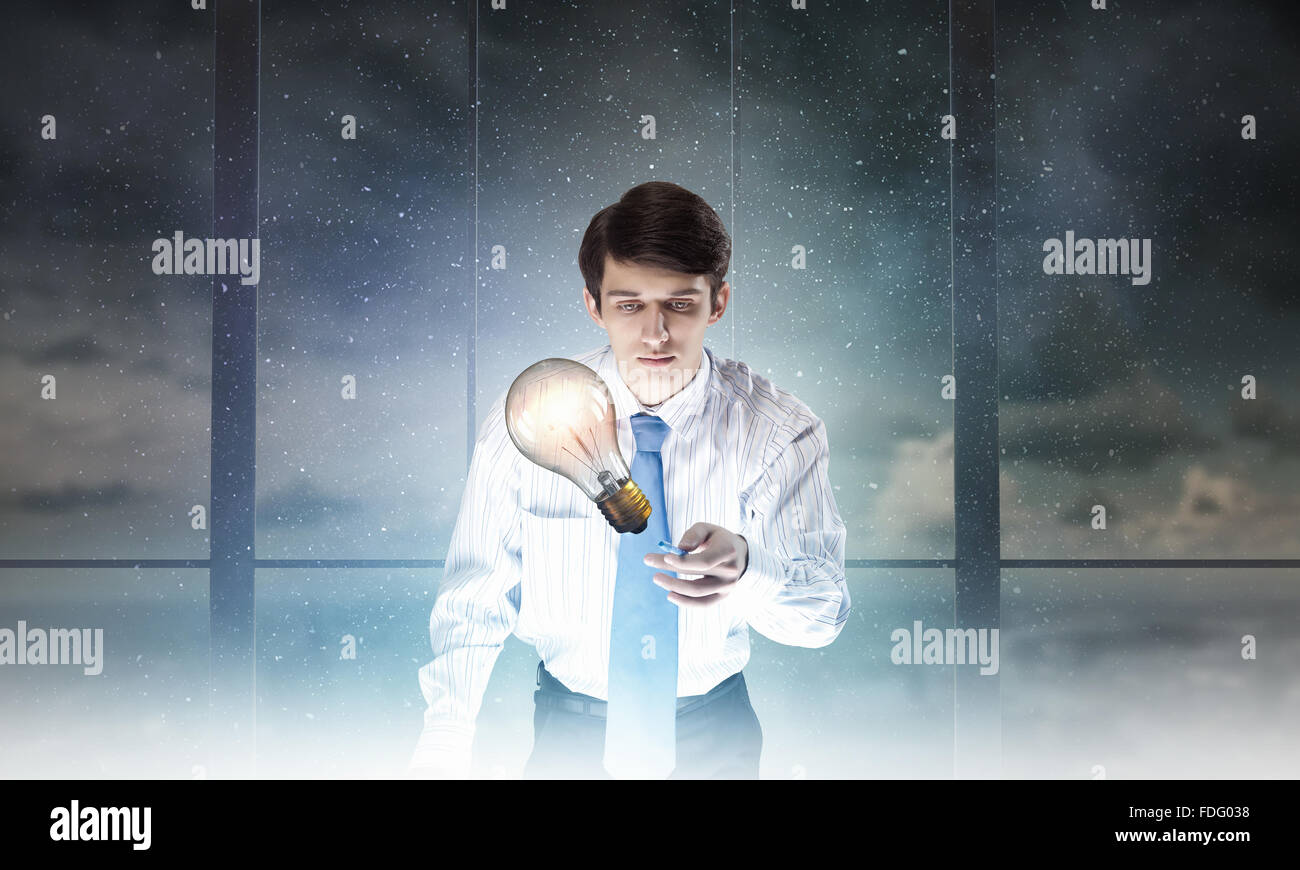 Young businessman examining glass glowing light bulb Stock Photo - Alamy