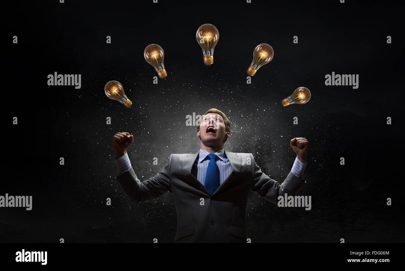 Young businessman with hands up screaming at light bulb above his head ...