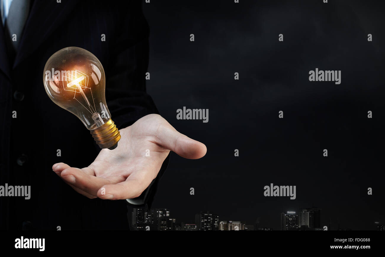 Businessman presenting glass glowing light bulb in his hand Stock Photo ...