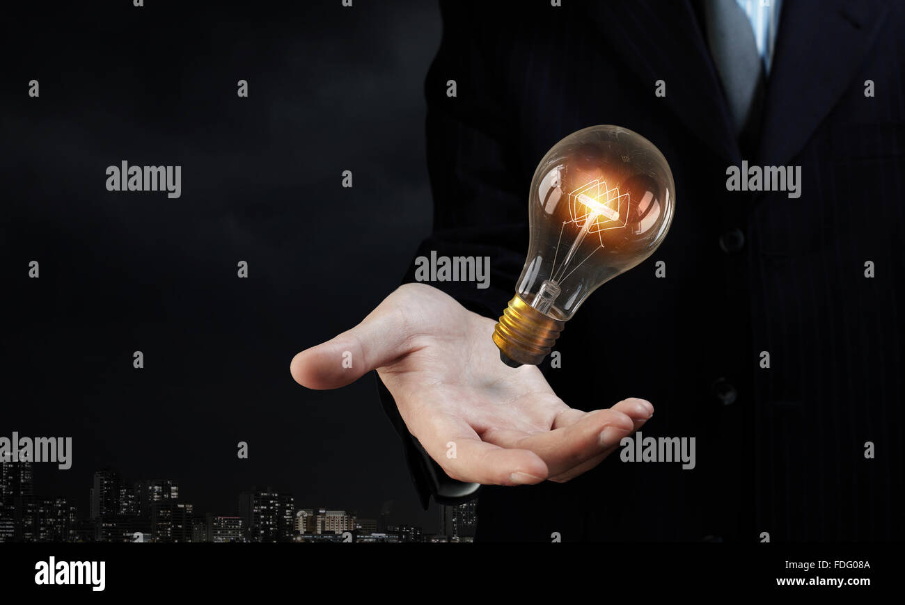 Businessman presenting glass glowing light bulb in his hand Stock Photo ...