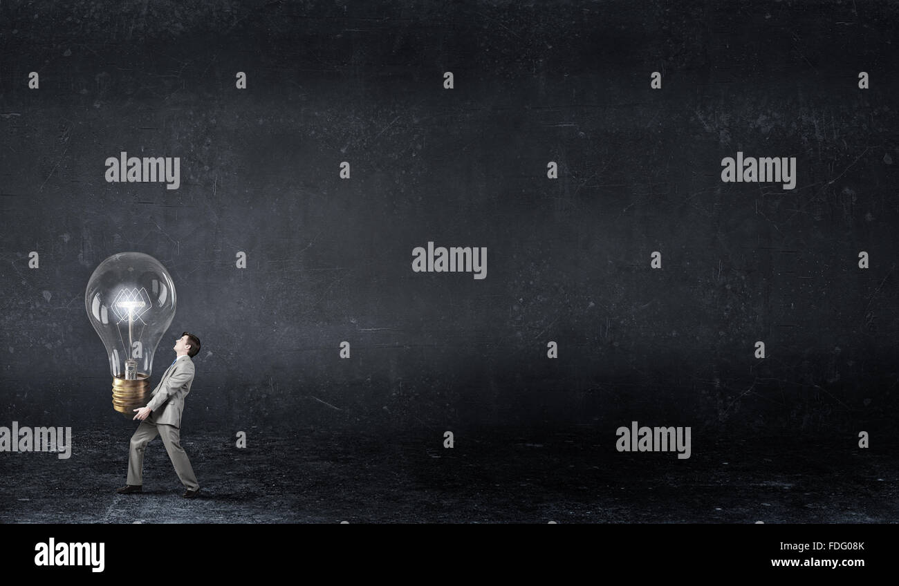 Young businessman carrying big light bulb in hands Stock Photo - Alamy