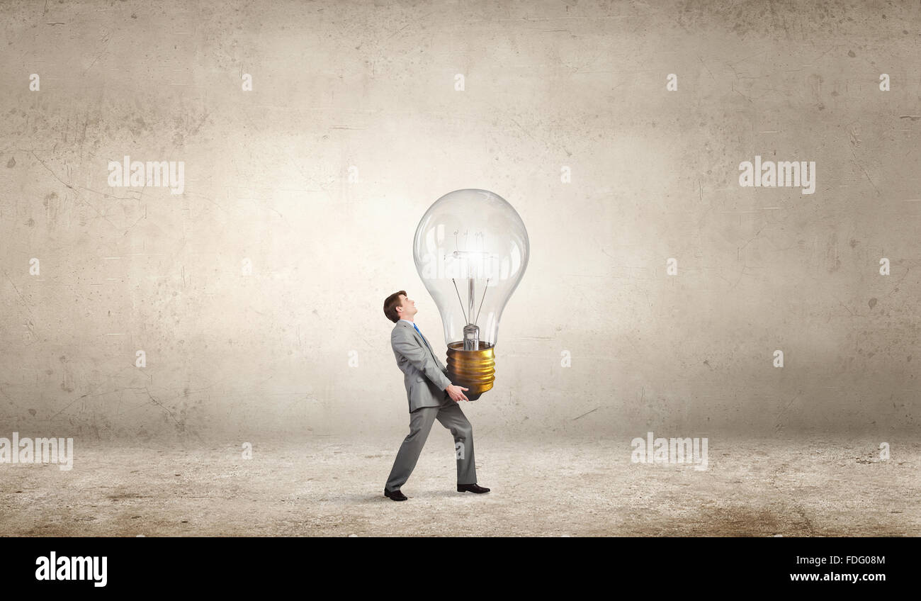 Young businessman carrying big light bulb in hands Stock Photo - Alamy