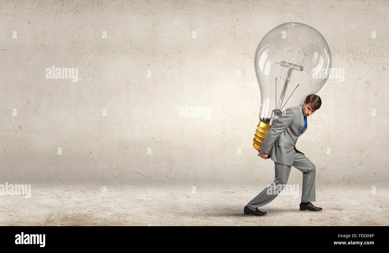 Young businessman carrying big light bulb on back Stock Photo - Alamy