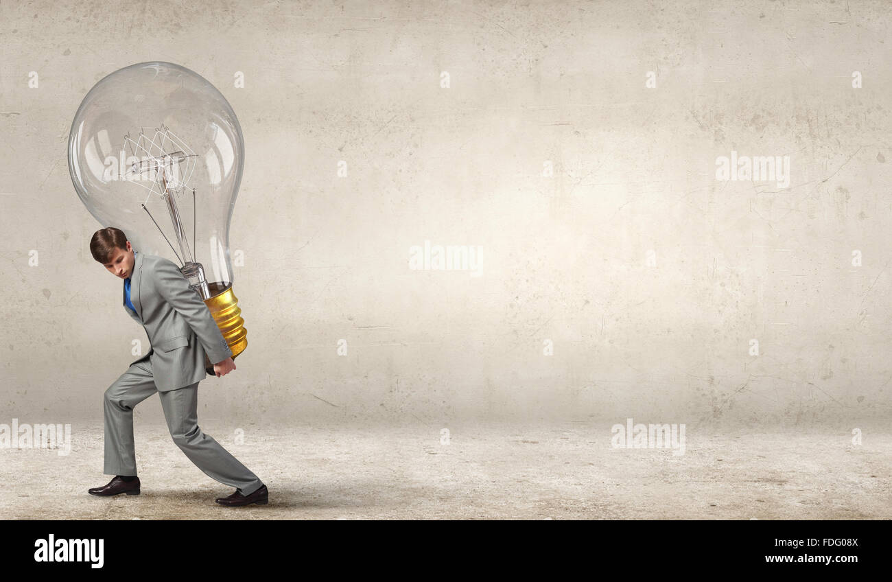Young businessman carrying big light bulb on back Stock Photo - Alamy