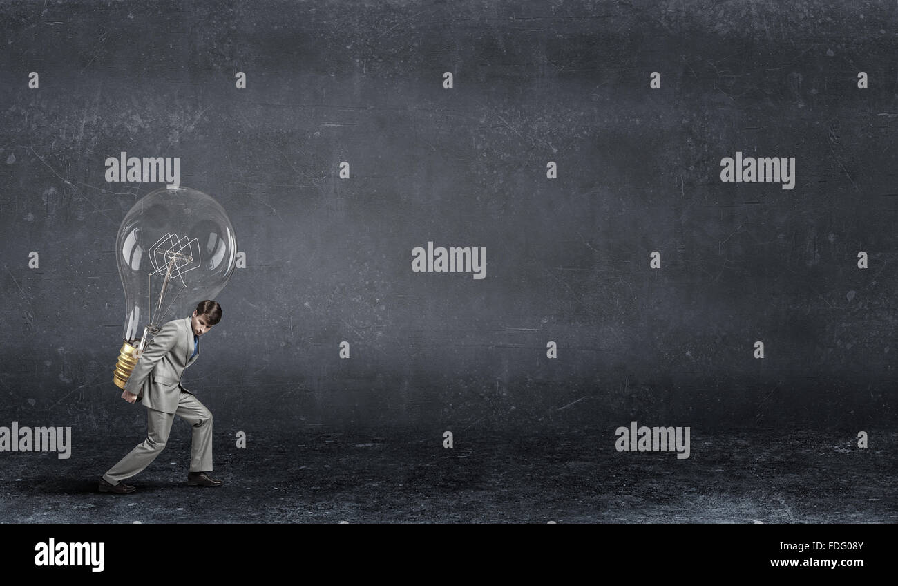 Young businessman carrying big light bulb on back Stock Photo - Alamy