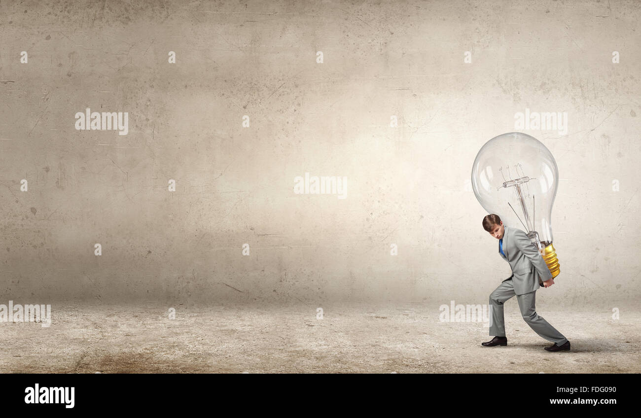 Young businessman carrying big light bulb on back Stock Photo - Alamy