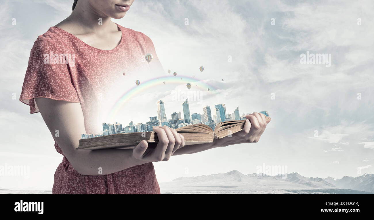 Young woman in red dress holding opened book with city model Stock ...