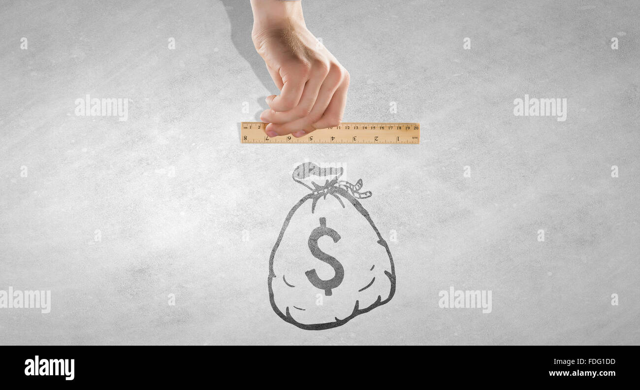 Close up of human hand measuring money bag with ruler Stock Photo - Alamy