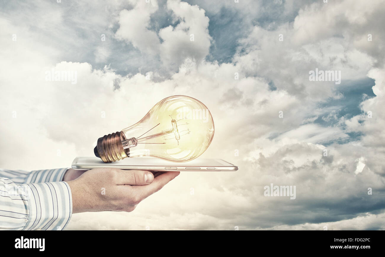 Human hands holding tablet pc with light bulb on it Stock Photo - Alamy