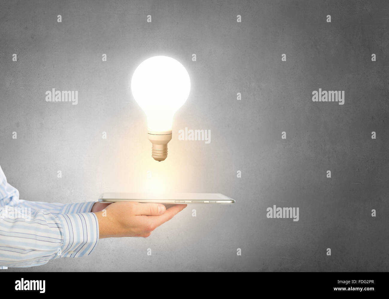 Human hands holding tablet pc with light bulb on it Stock Photo - Alamy