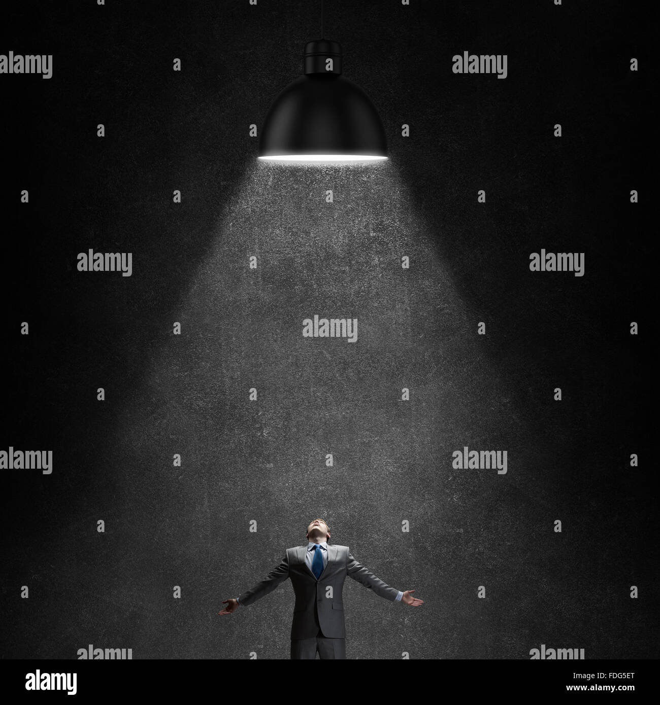 Businessman with hands spread apart standing in lamp light from above ...