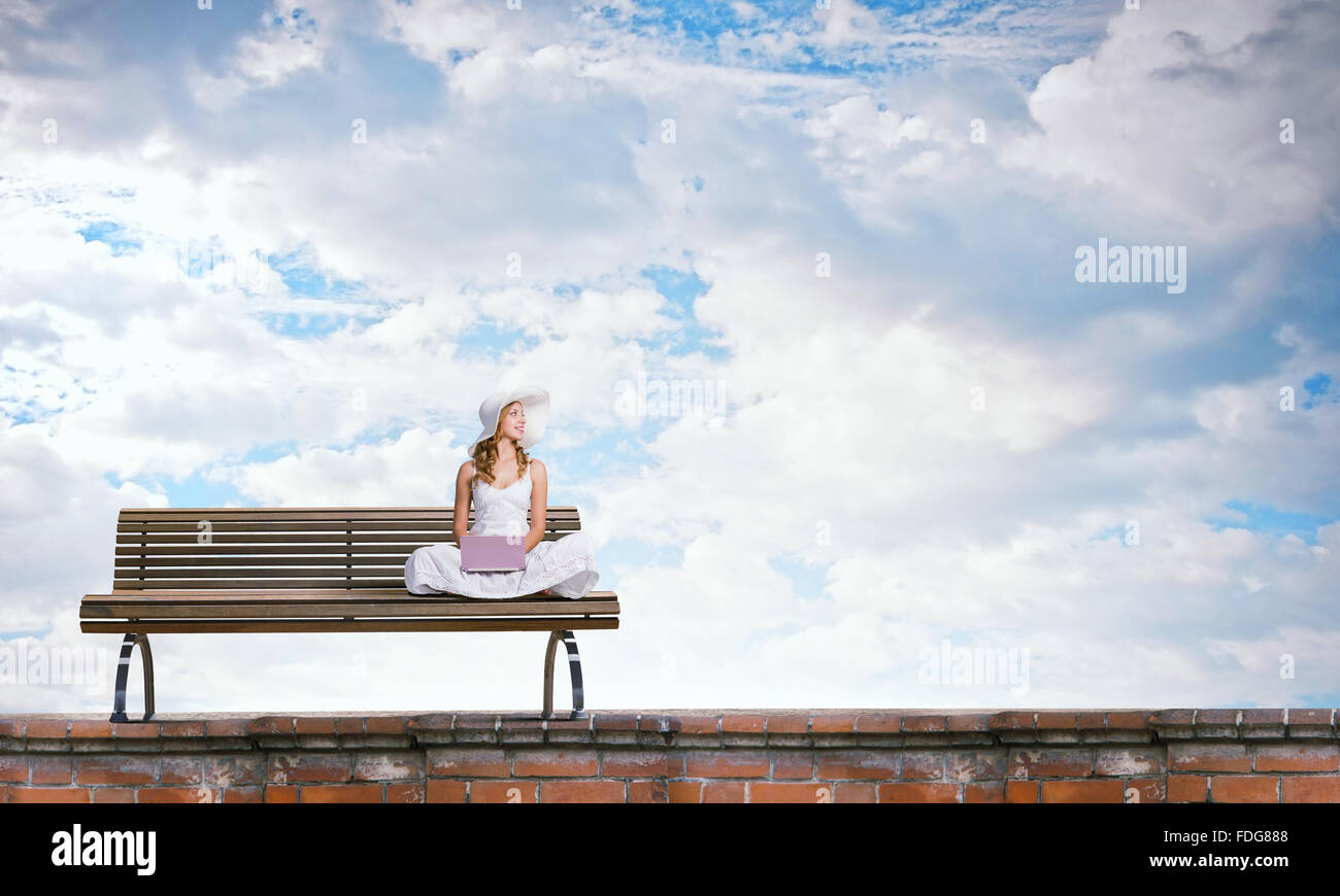 Young lady sitting on bench and using laptop Stock Photo - Alamy