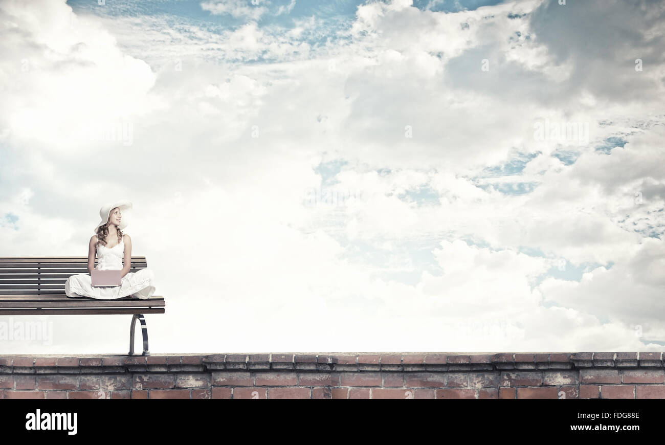Young lady sitting on bench and using laptop Stock Photo - Alamy