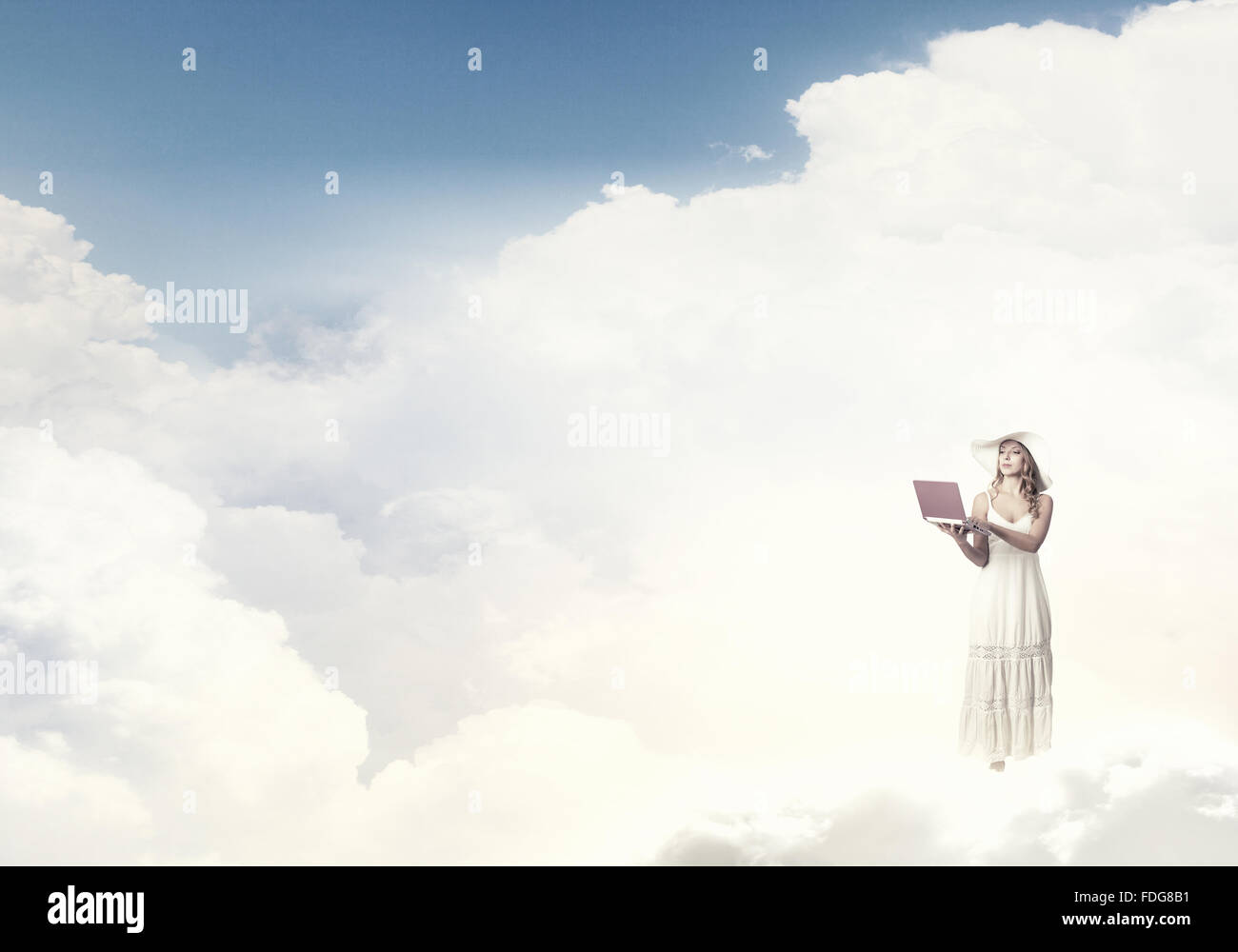 Young lady standing on cloud and using laptop Stock Photo - Alamy