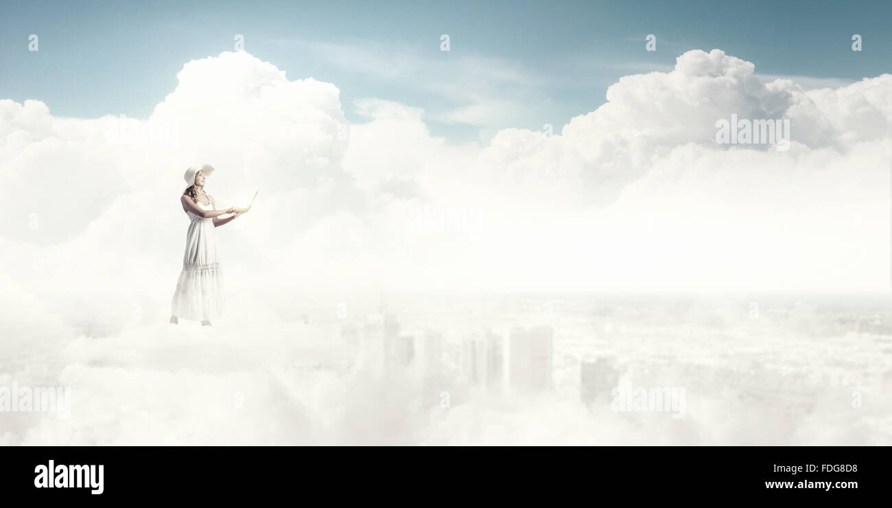 Young lady standing on cloud and using laptop Stock Photo - Alamy