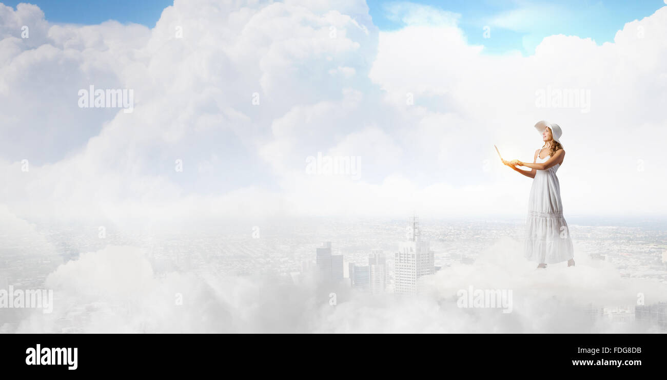 Young lady standing on cloud and using laptop Stock Photo - Alamy