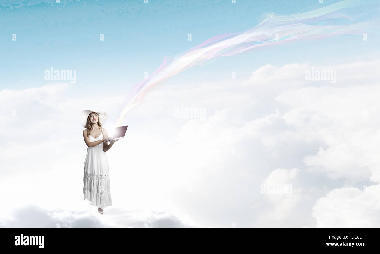 Young lady standing on cloud and using laptop Stock Photo - Alamy