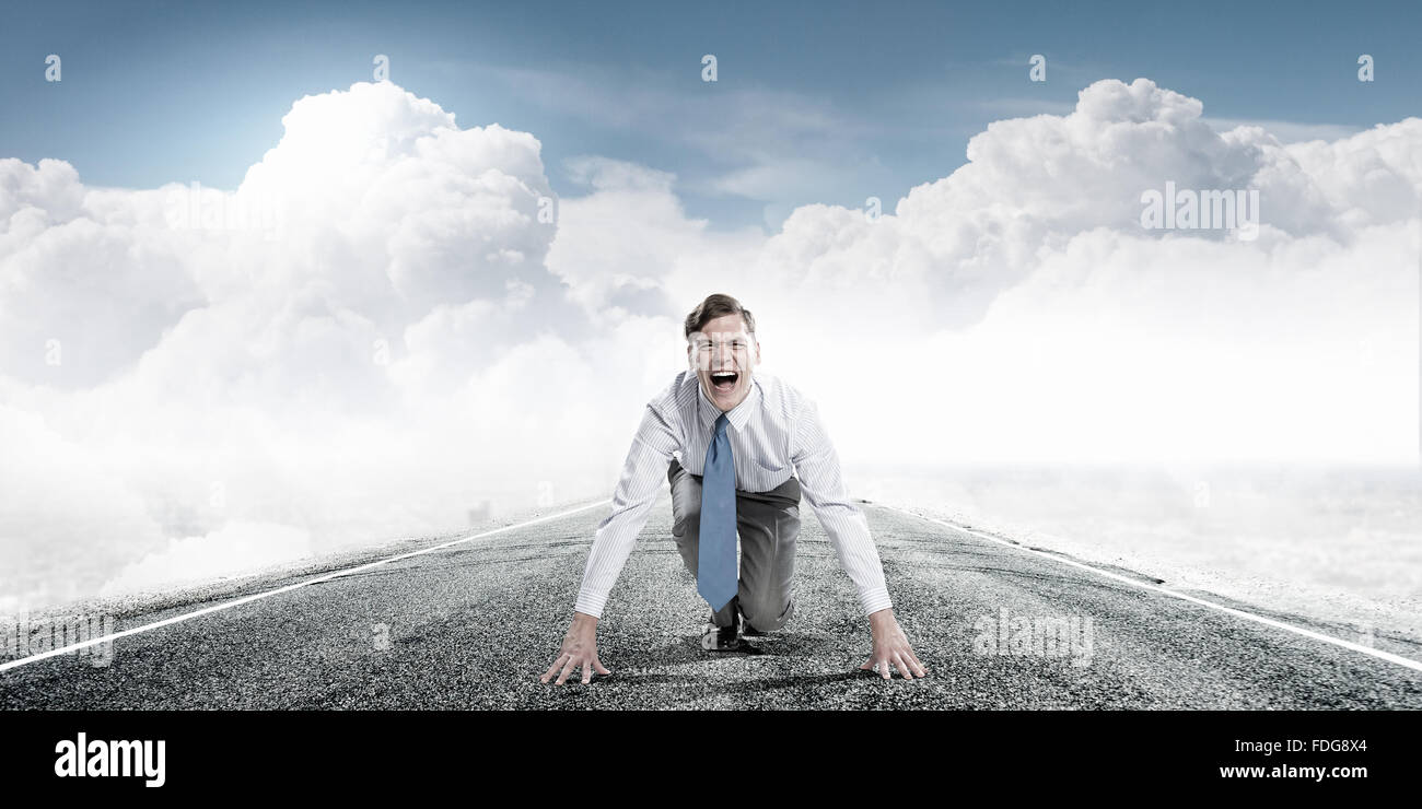 Young determined businessman in starting position ready to compete ...