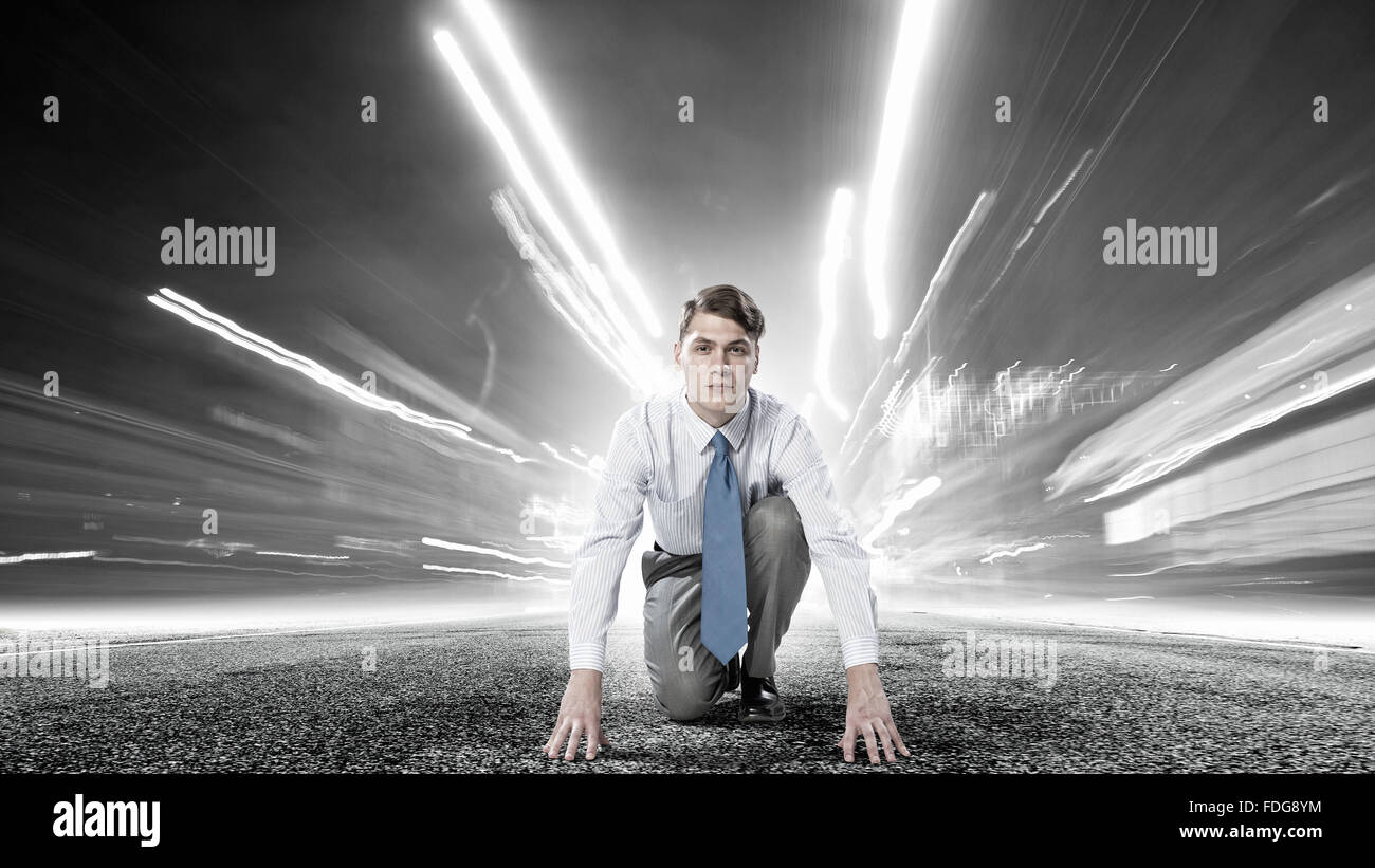 Young determined businessman in starting position ready to compete ...