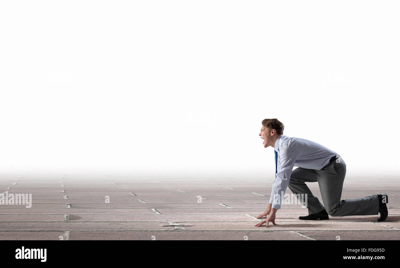 Young determined businessman in starting position ready to compete ...