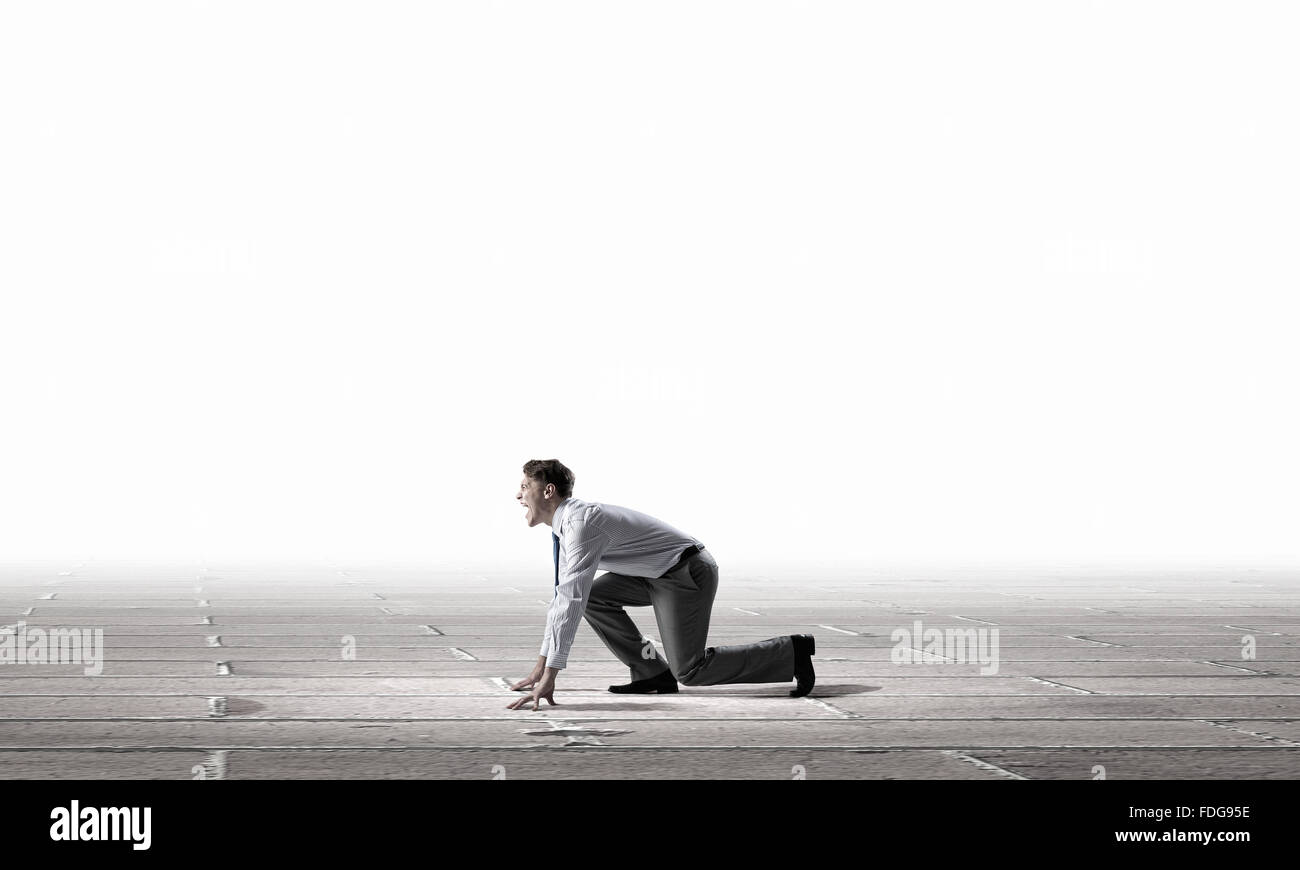 Young determined businessman in starting position ready to compete ...