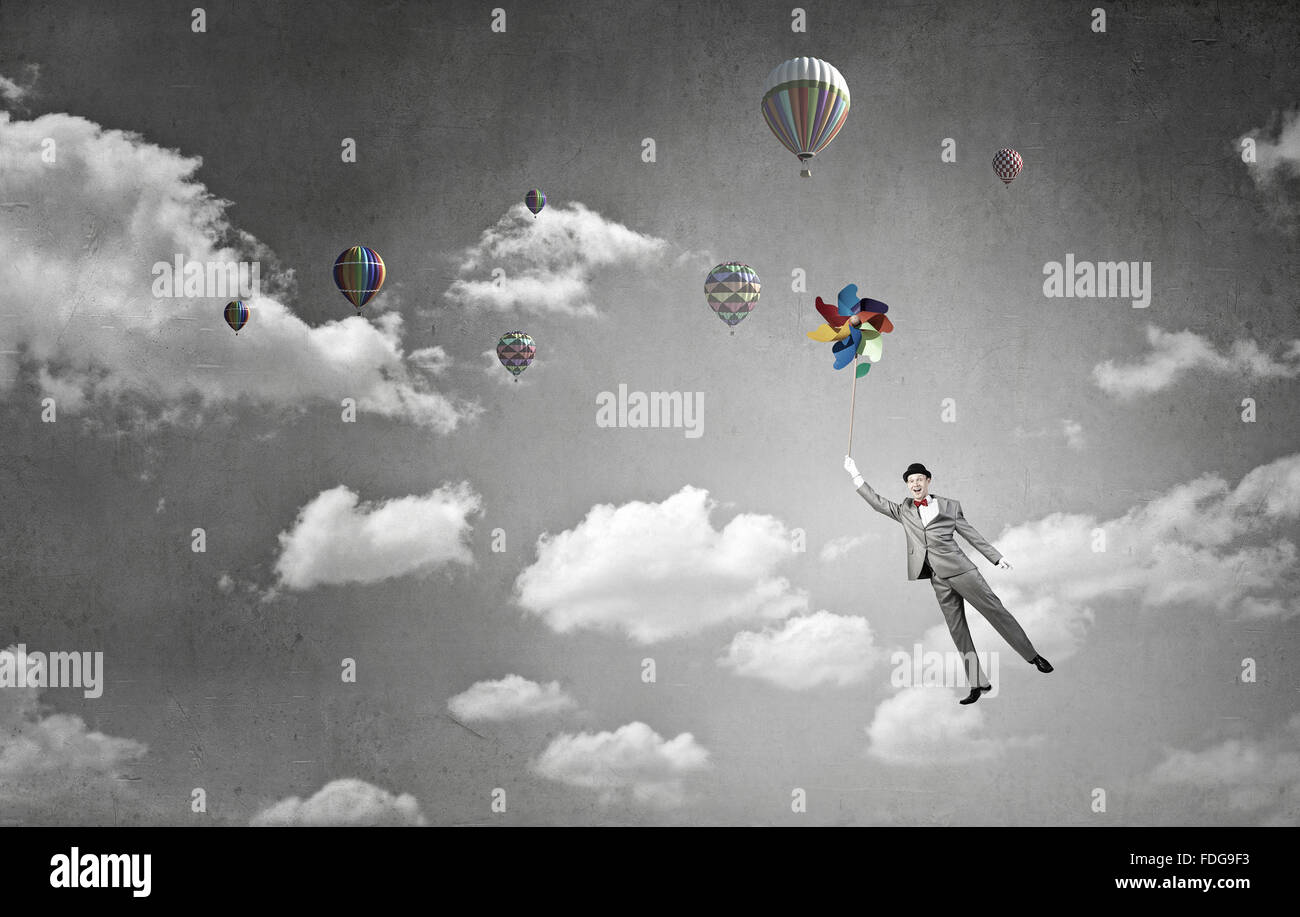 Young happy businessman in hat flying in sky on colorful windmill Stock ...