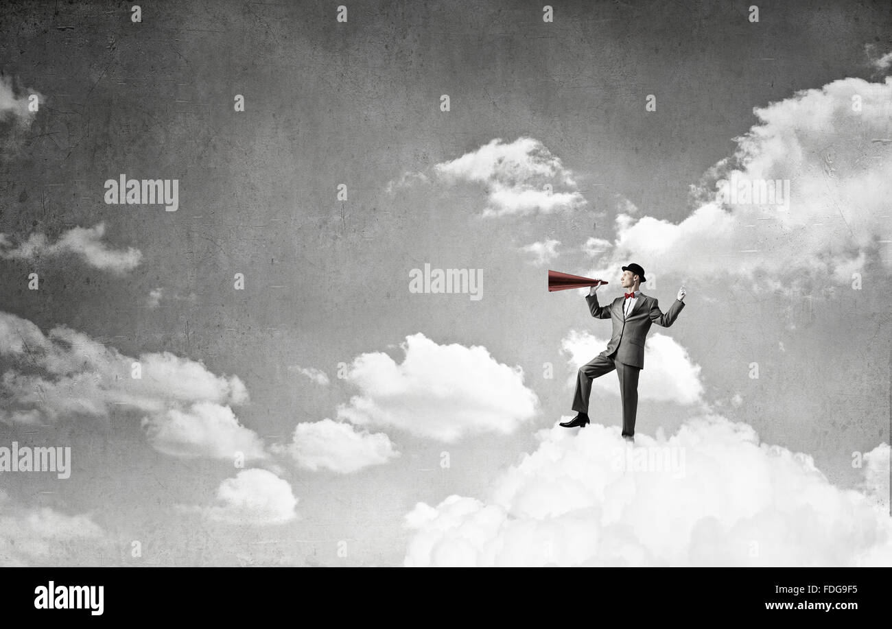 Young businessman on cloud screaming emotionally in paper trumpet Stock ...