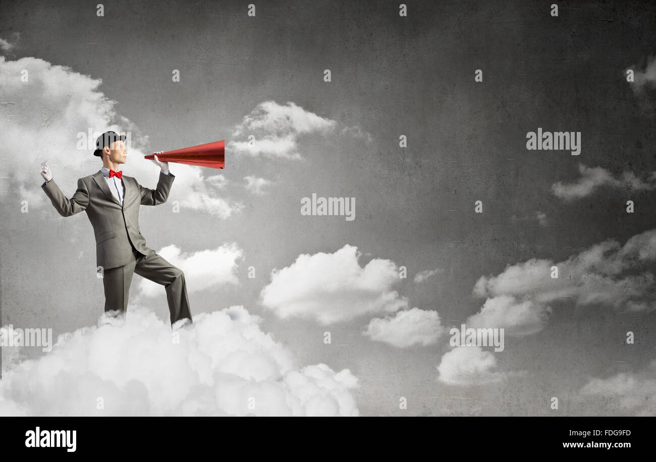 Young businessman on cloud screaming emotionally in paper trumpet Stock ...