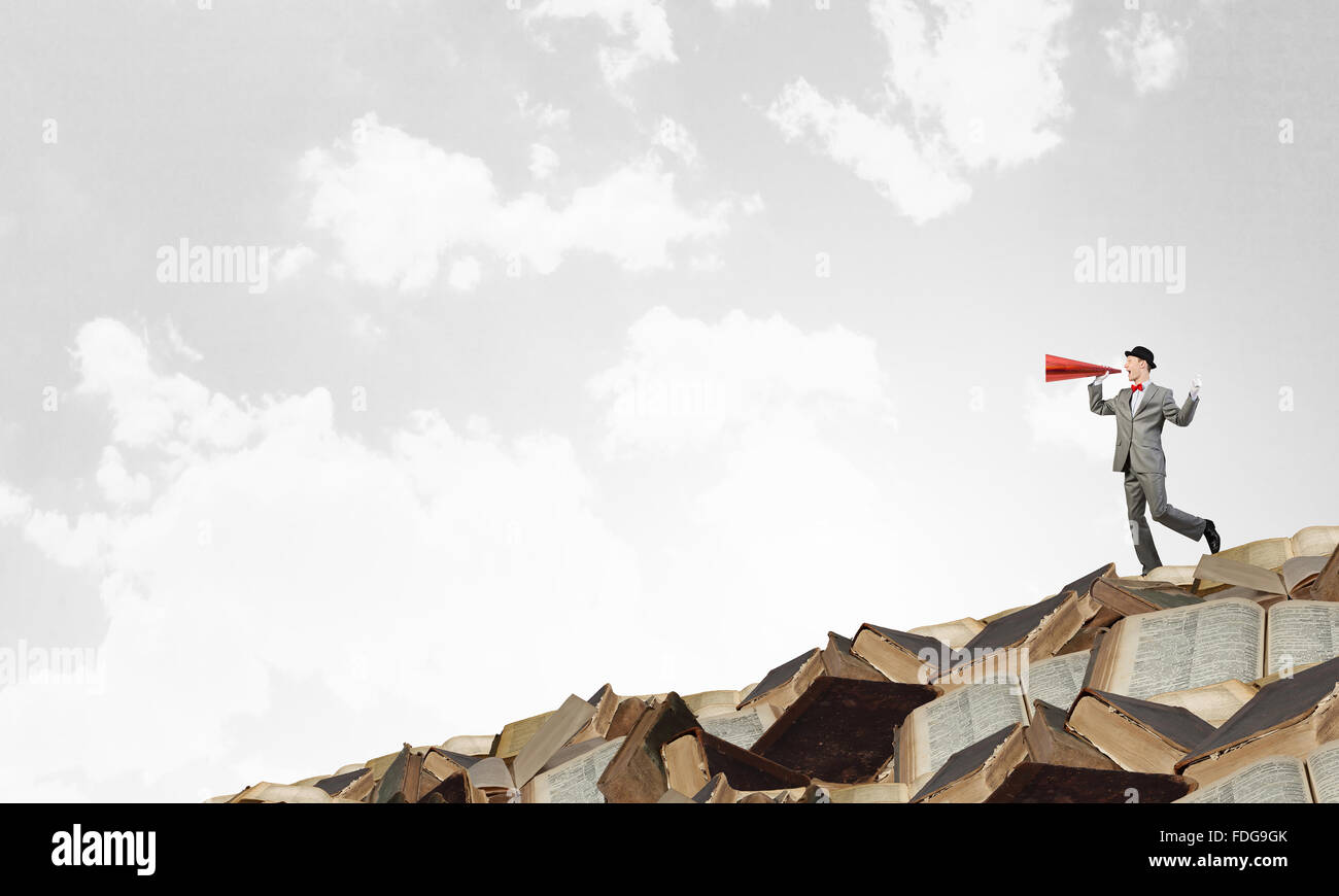 Young businessman on pile of books screaming emotionally in paper ...