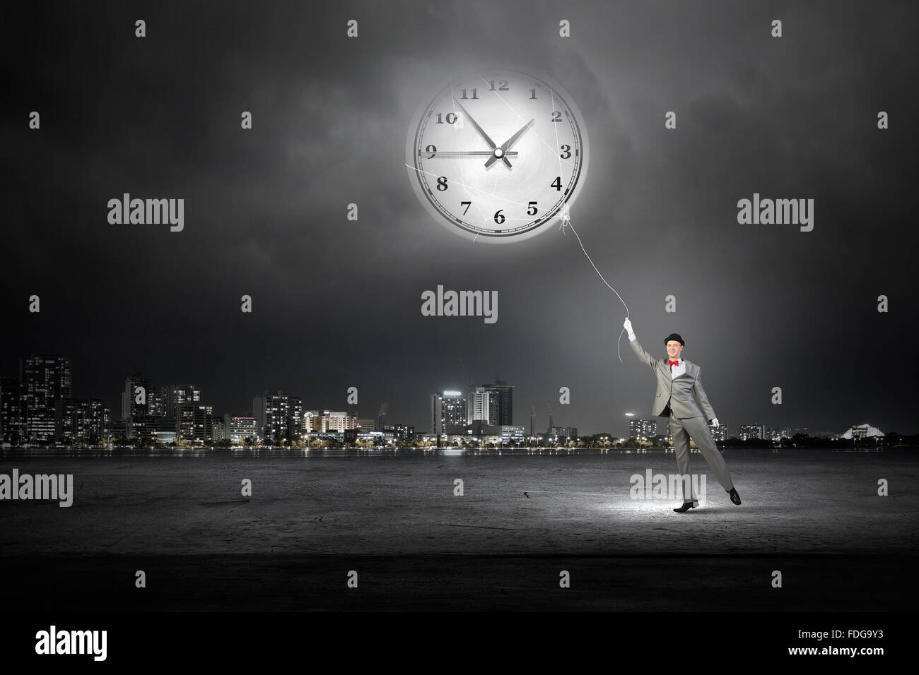 Young businessman trying to turn back time by pulling clock with rope ...