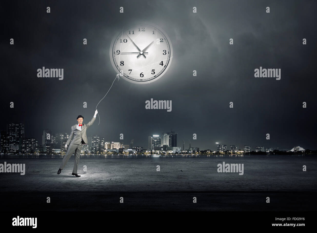 Young businessman trying to turn back time by pulling clock with rope ...