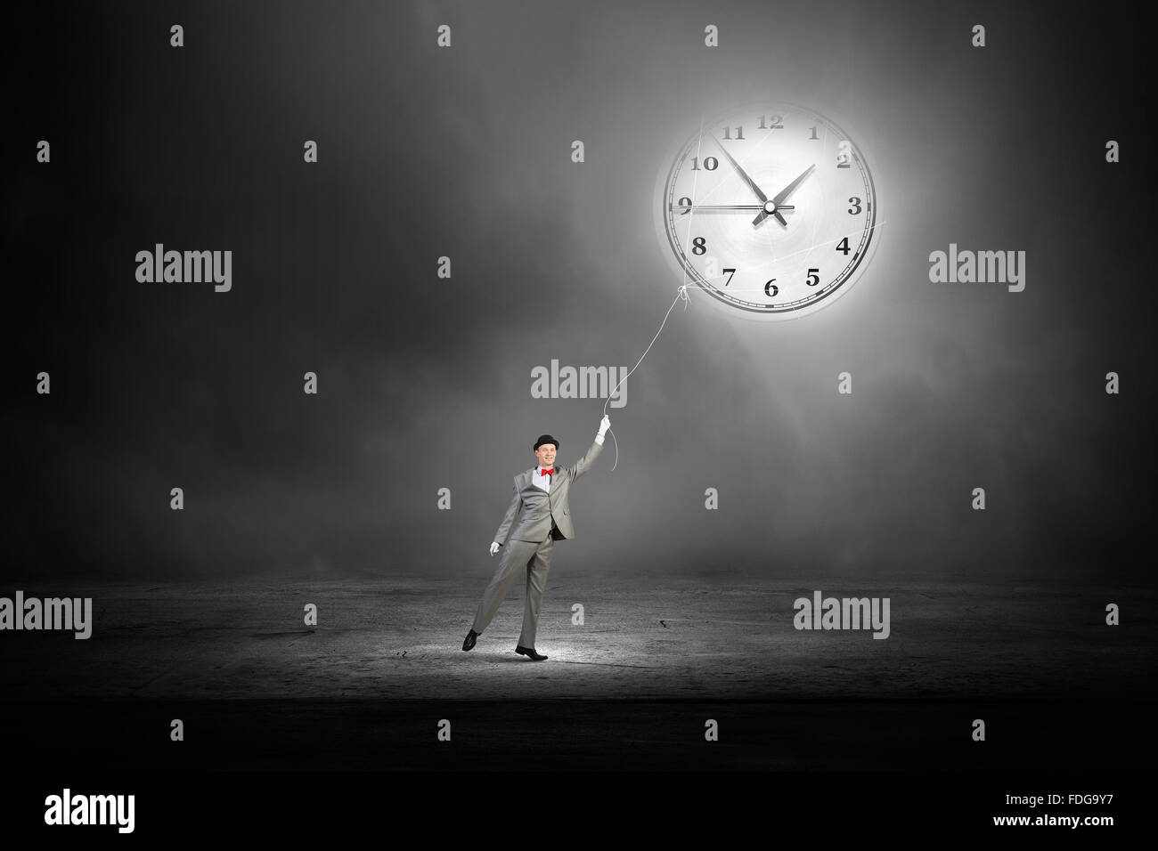 Young businessman trying to turn back time by pulling clock with rope ...
