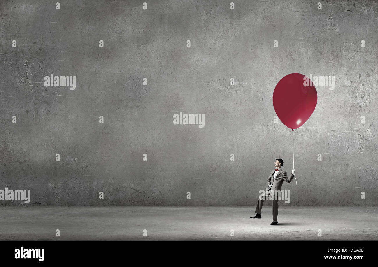 Young businessman walking with colorful balloon on rope Stock Photo - Alamy