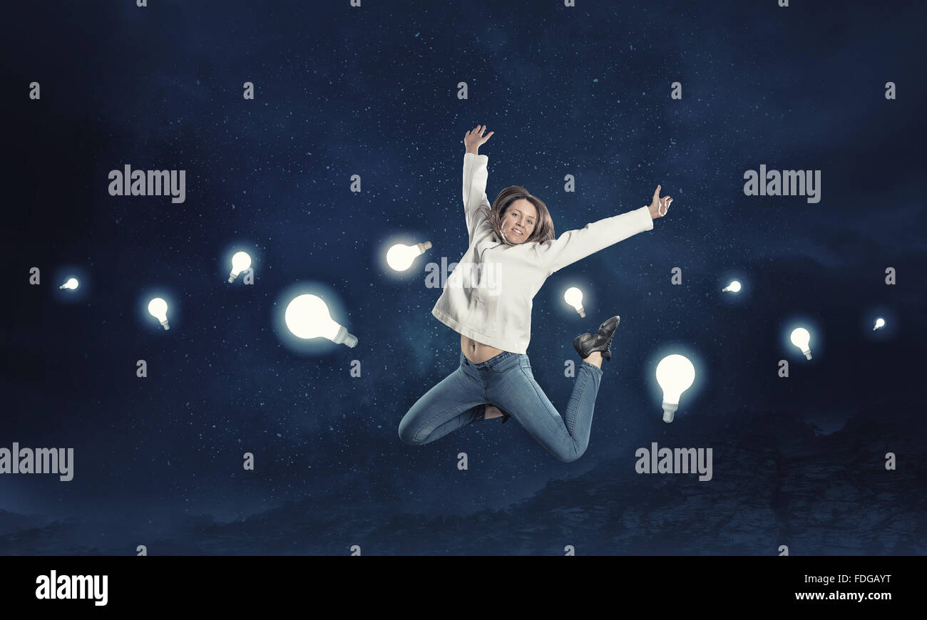 Young woman dancer jumping among light bulbs on dark background Stock ...