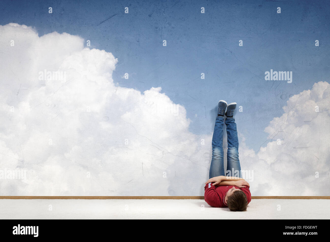 Young man lying on floor with legs raised up Stock Photo - Alamy