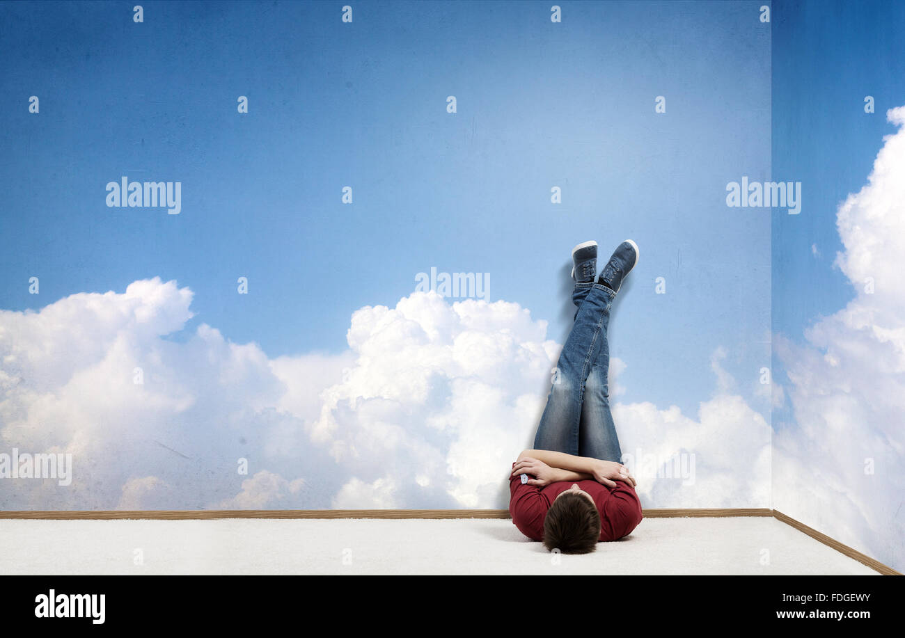 Young man lying on floor with legs raised up Stock Photo - Alamy