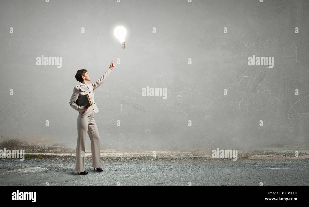 Adult woman in suit with old book in hand pointing at light bulb Stock ...