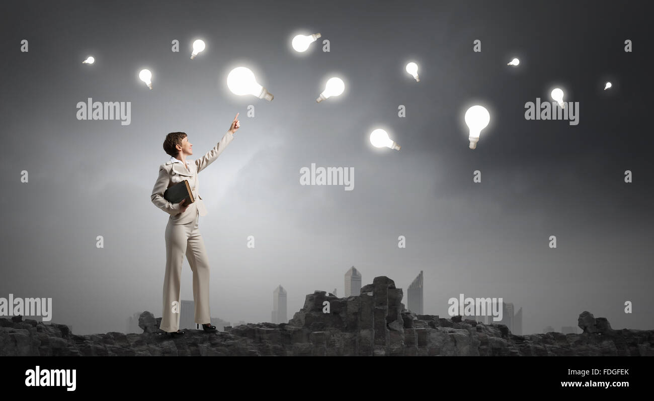 Adult woman in suit with old book in hand pointing at light bulb Stock ...