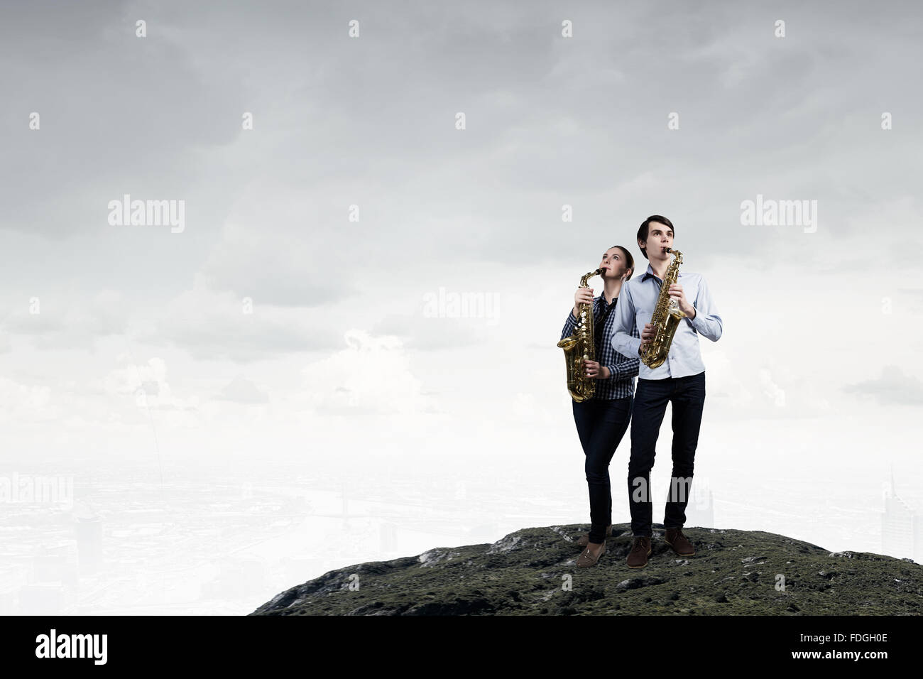 Duet of young man and woman musicians playing saxophones Stock Photo ...
