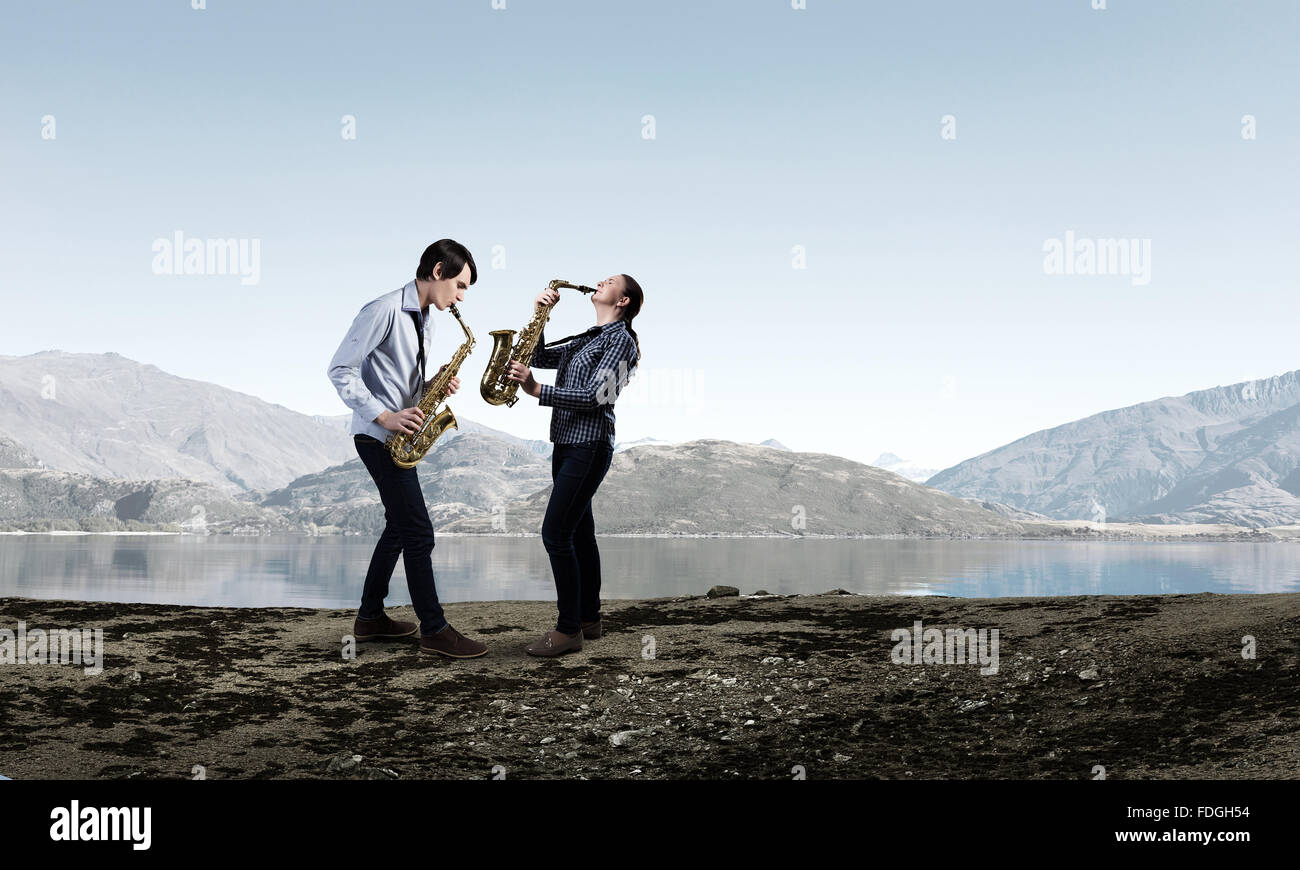 Duet of young man and woman musicians playing saxophones Stock Photo ...