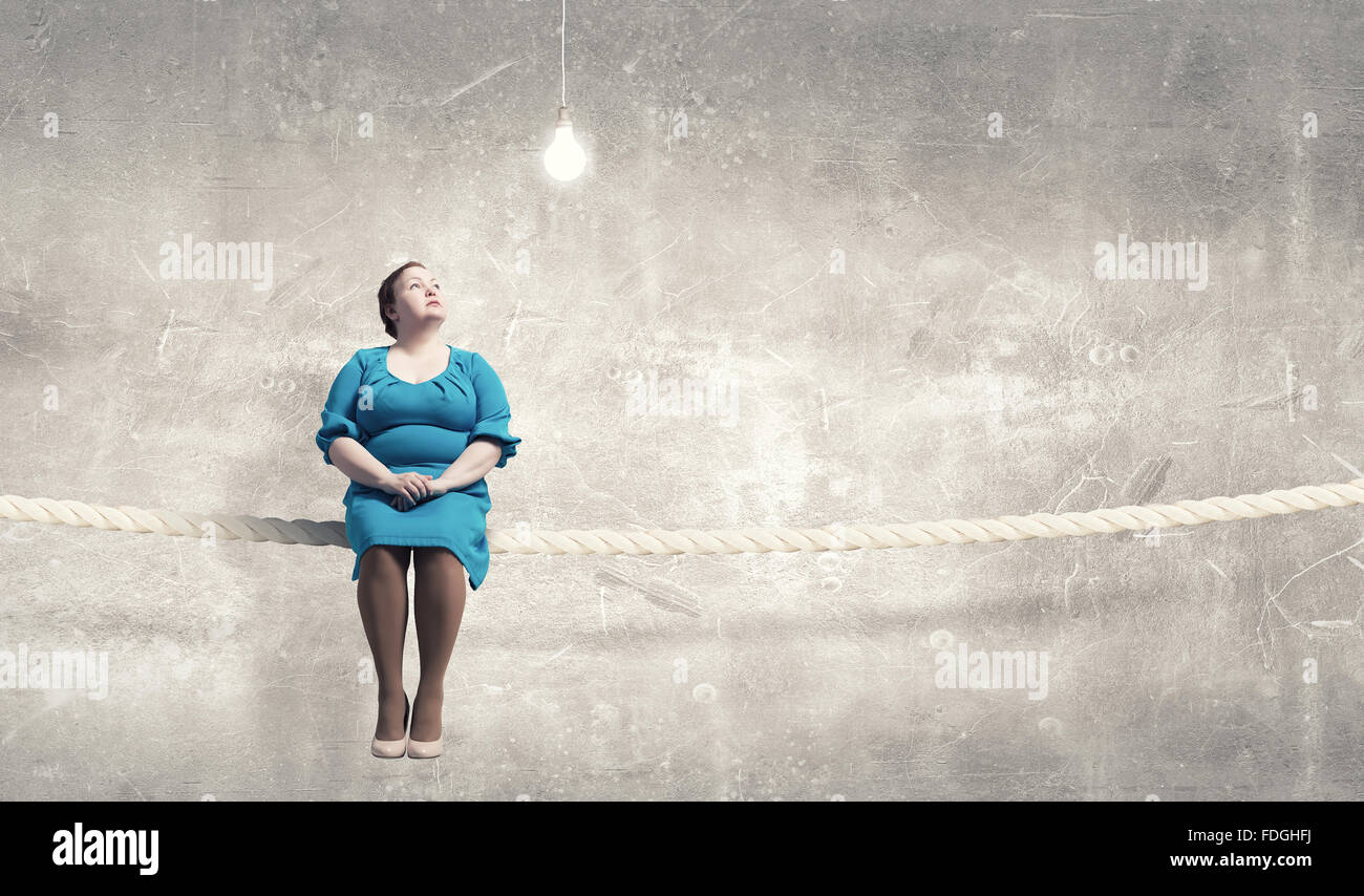 Middle aged stout woman in blue dress sitting on rope Stock Photo - Alamy