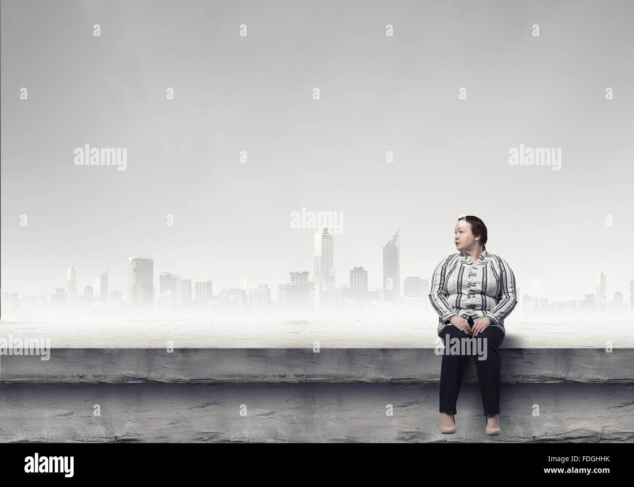 Middle aged stout woman sitting on building roof Stock Photo - Alamy