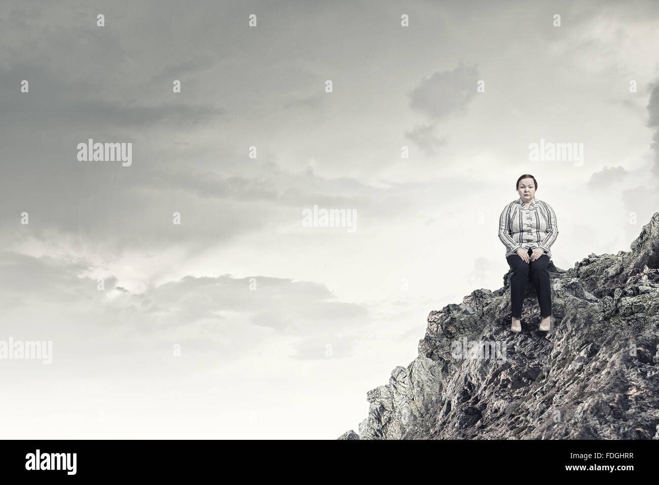 Middle aged stout woman sitting on rock top Stock Photo - Alamy