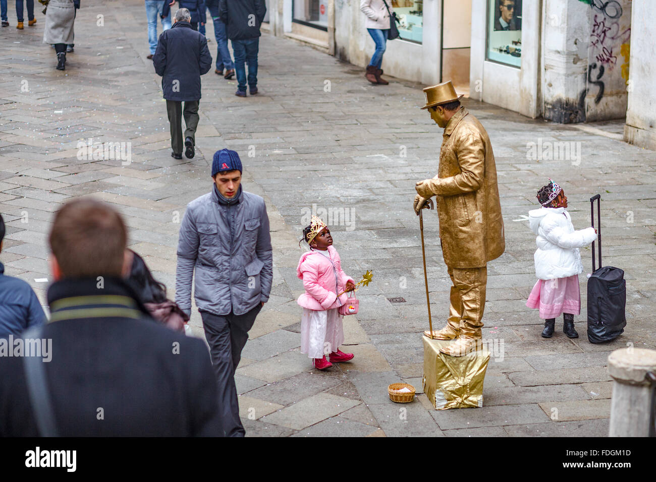 little girl watching with interest a street performer disguise in gold ...