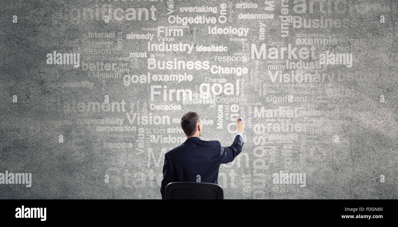 Rear view of businessman writing leadership conceptual words on wall ...