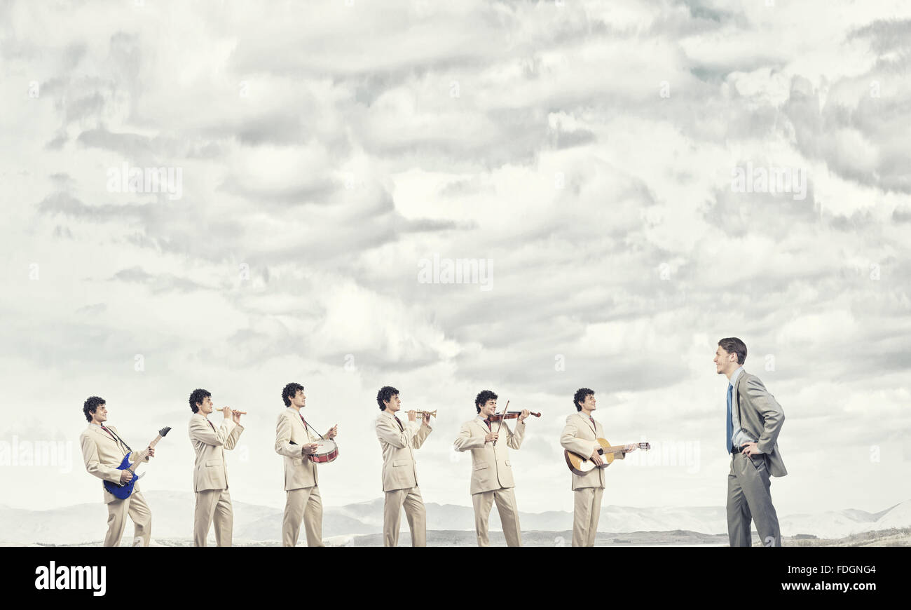 Man orchestra in suit playing different music instruments Stock Photo ...